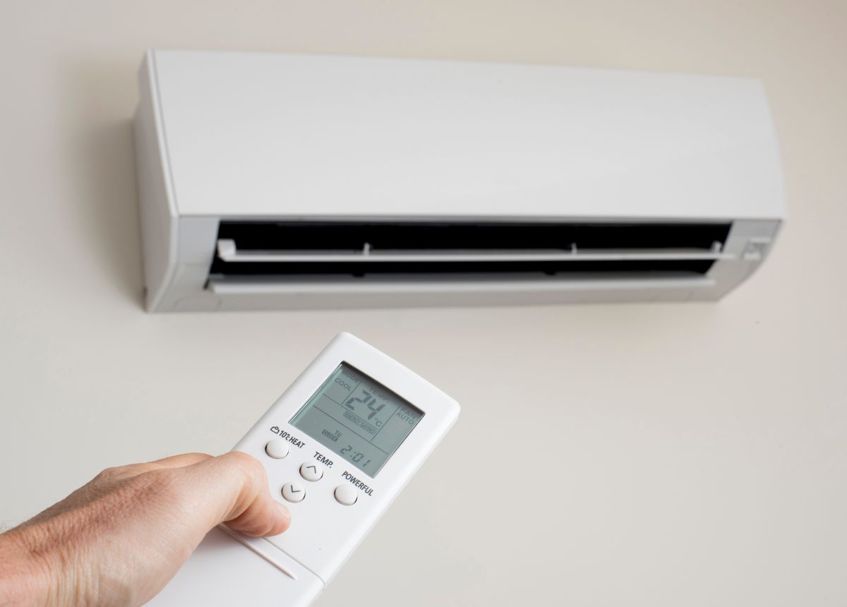 What does the sensor button on the air conditioner remote do?